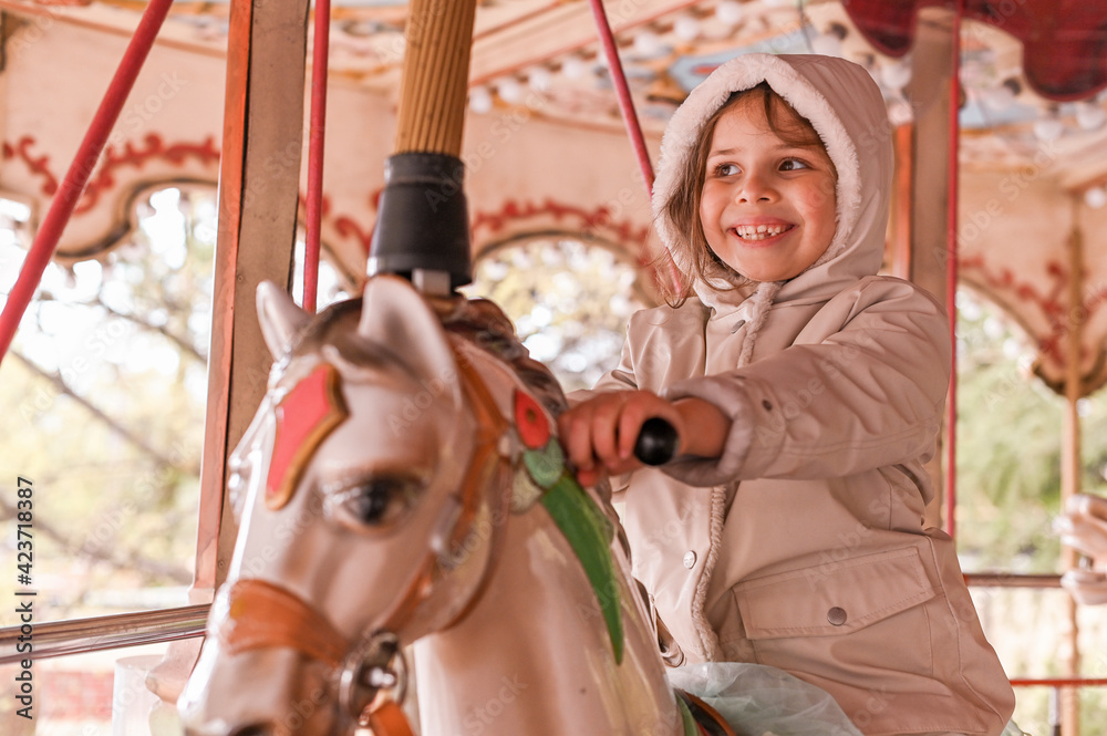 The girl in bright clothes rides on the carousel on a holiday. Happy ...