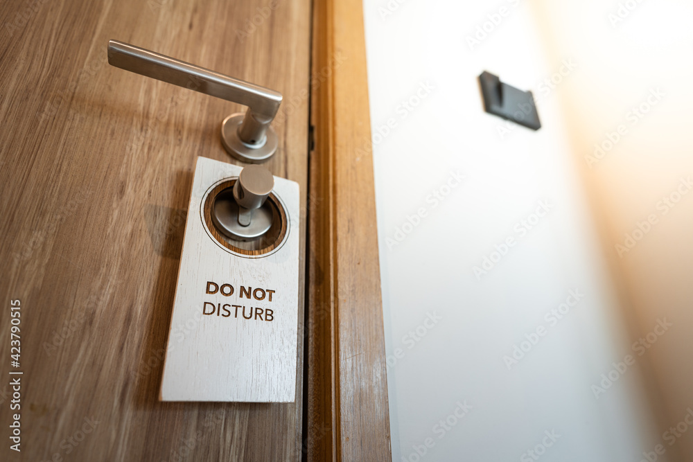 "Do not disturb" wooden plate sign which is hanging on the door handle ...