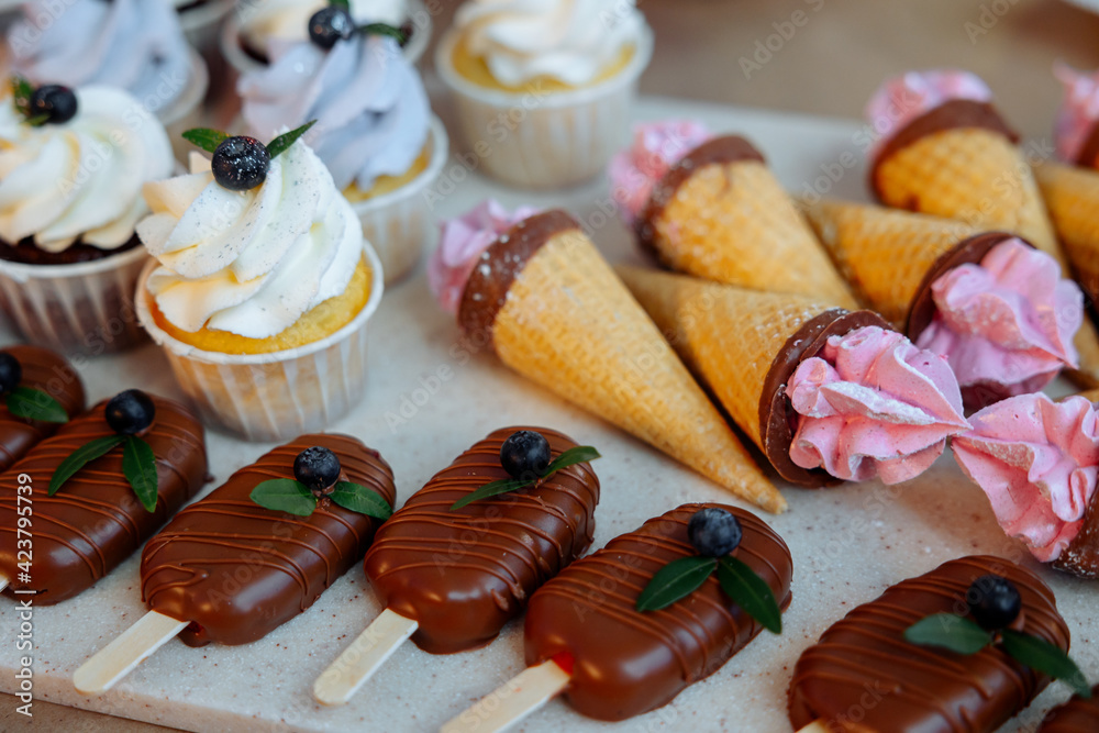 sweet table of cakes, cupcakes, ice cream on a stick and in a waffle ...