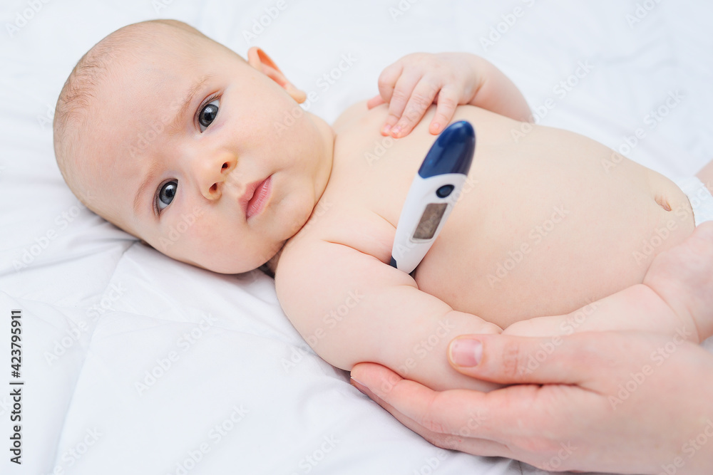 a baby with a thermometer under his armpit is measured by his mother's ...