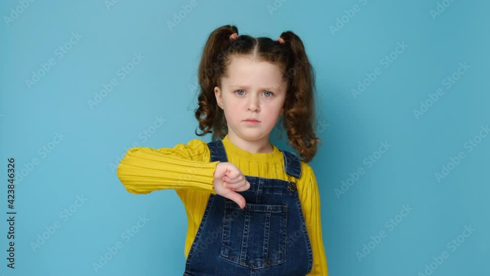 Angry frown facial expressions little girl look at camera show thumb ...