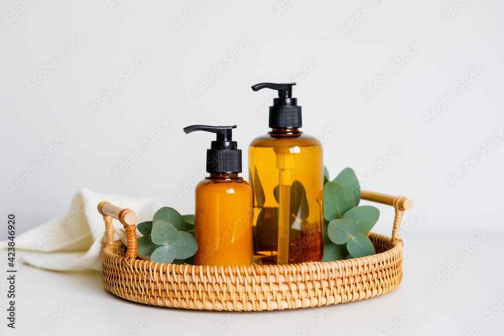 Amber glass liquid soap dispenser bottles and eucalyptus in rattan tray ...