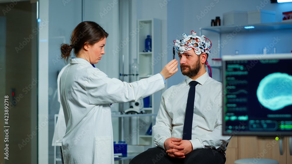 Man sitting on neurological chair with brainwave scanning headset while ...