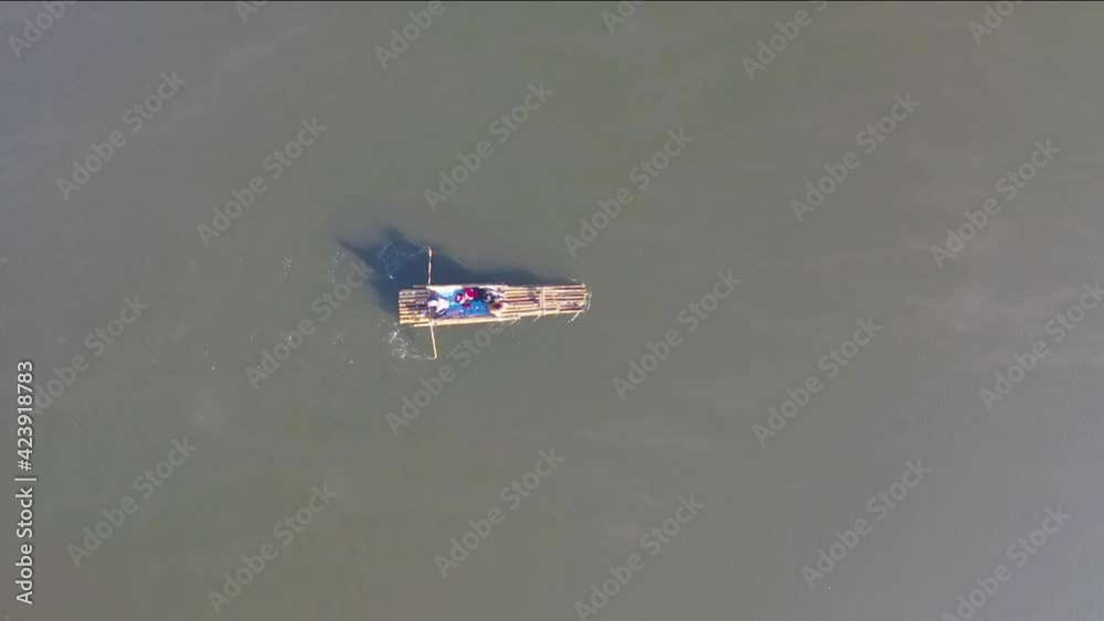 Aerial top view of a tourist paddling a wooden raft, kayak, or boat in ...