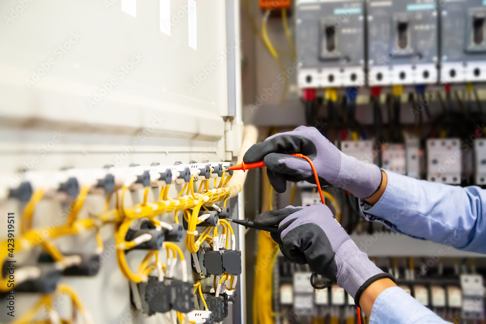 Electrical engineer using digital multi-meter measuring equipment to ...