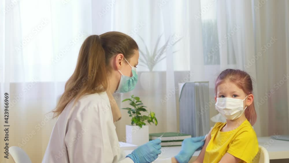 Little cute girl Child in yellow with mask receiving vaccination ...
