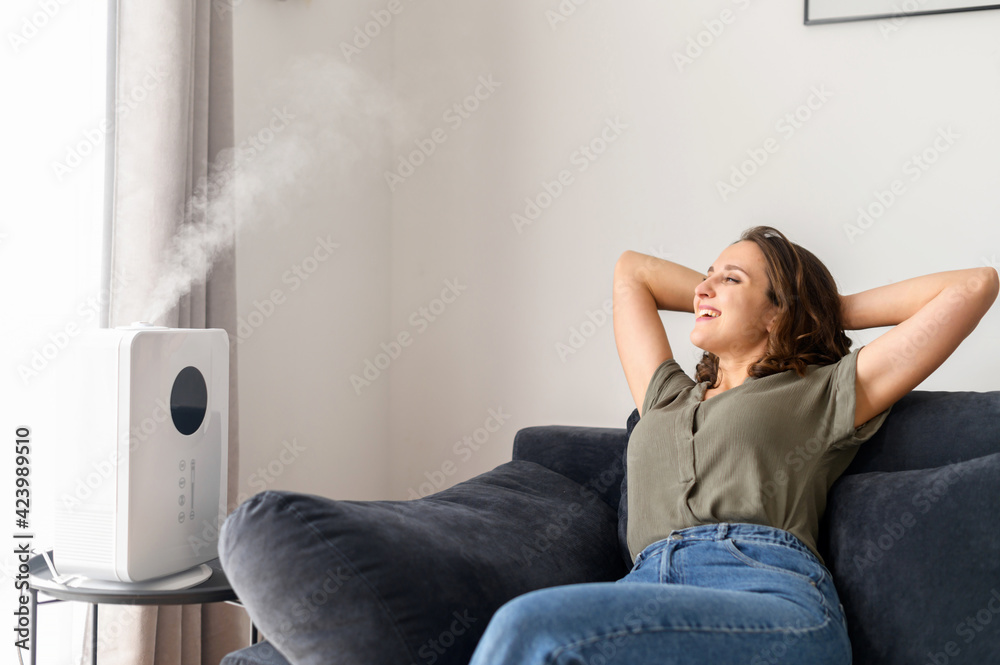 Calm and relaxed young woman enjoying fresh moisturized air from modern ...
