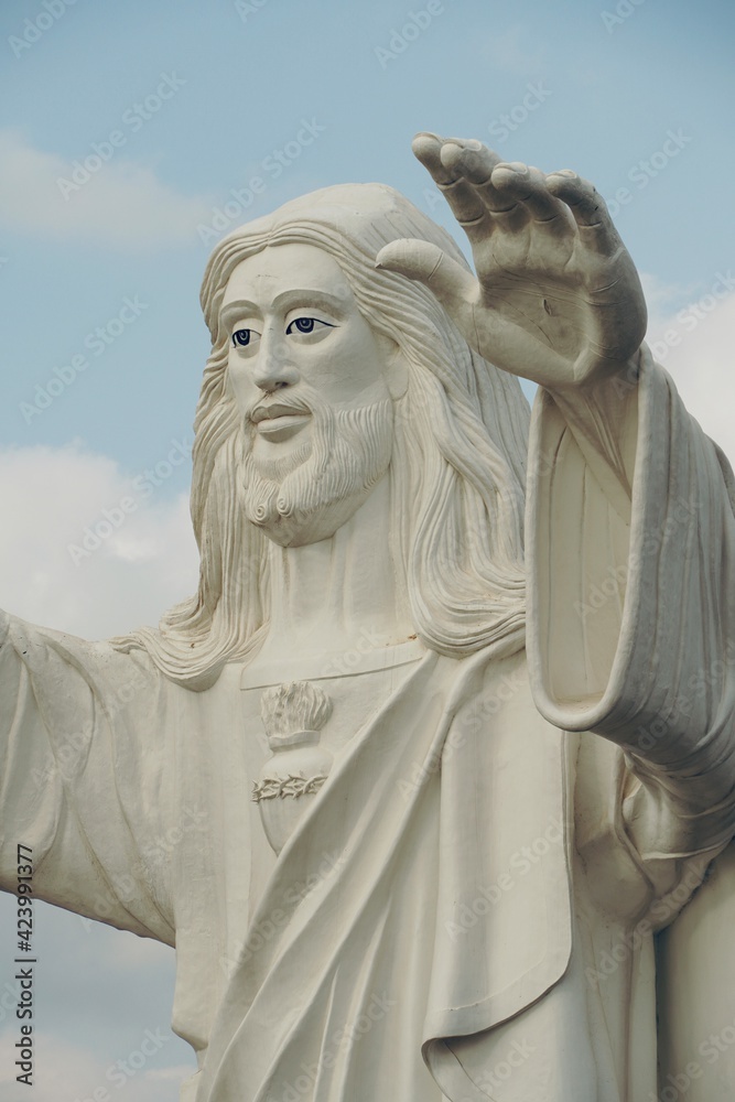 Jesus statue standing and blessing with both the hands against blue sky ...