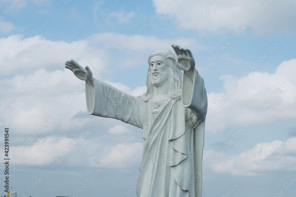 Jesus statue standing and blessing with both the hands against blue sky ...