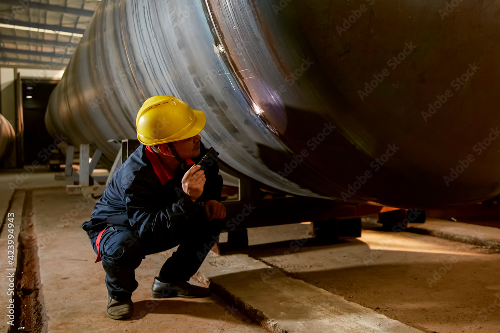 Asian workers are using flashlights to look at the details of the steel ...