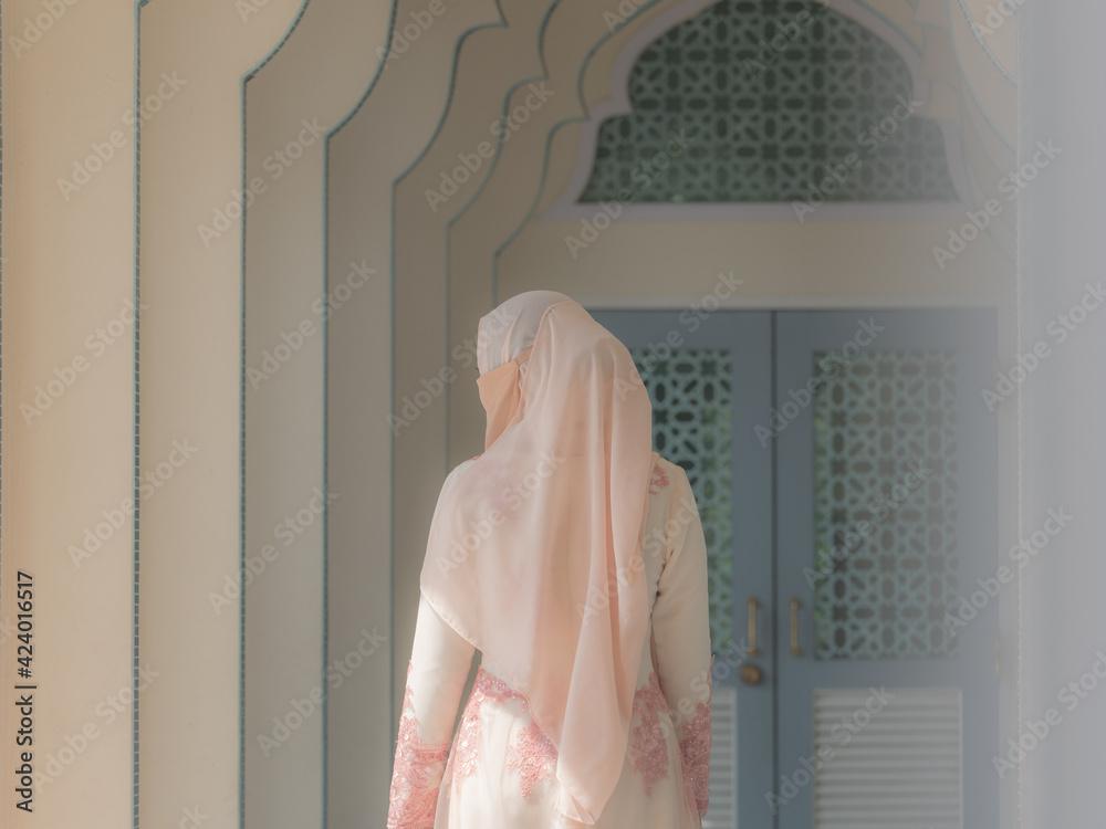 Rear view of Muslim woman in traditional clothing and hijab walking in ...