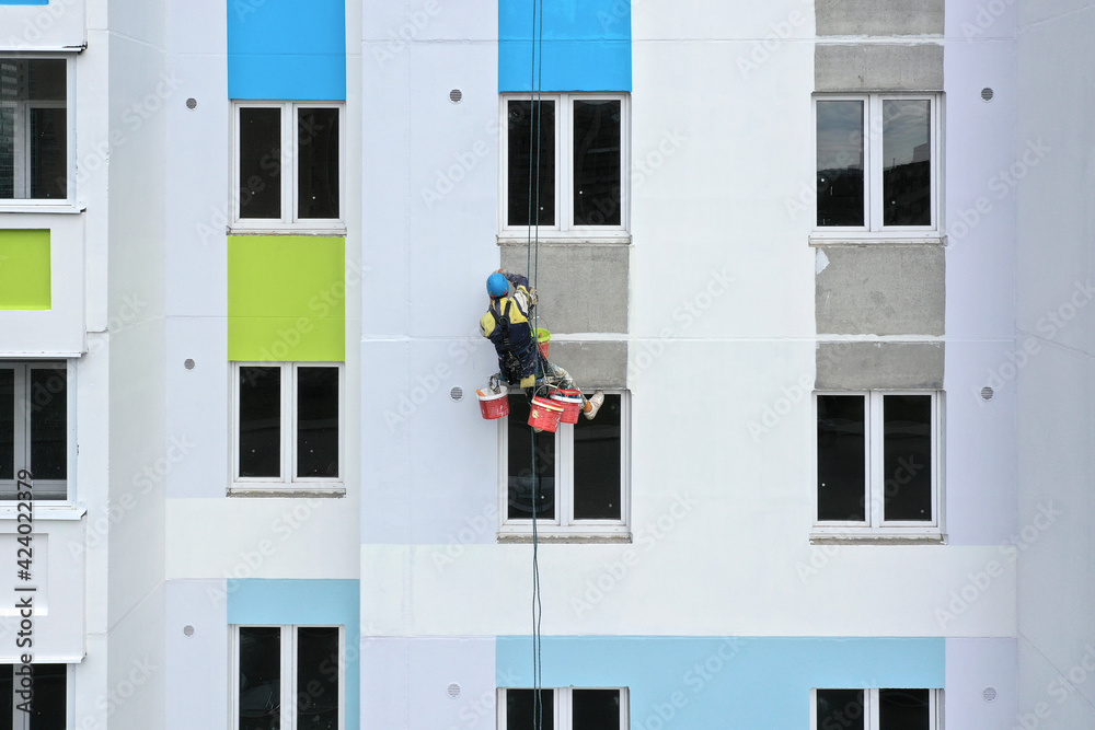 A high-rise painter is painting the facade of a multi-storey building ...