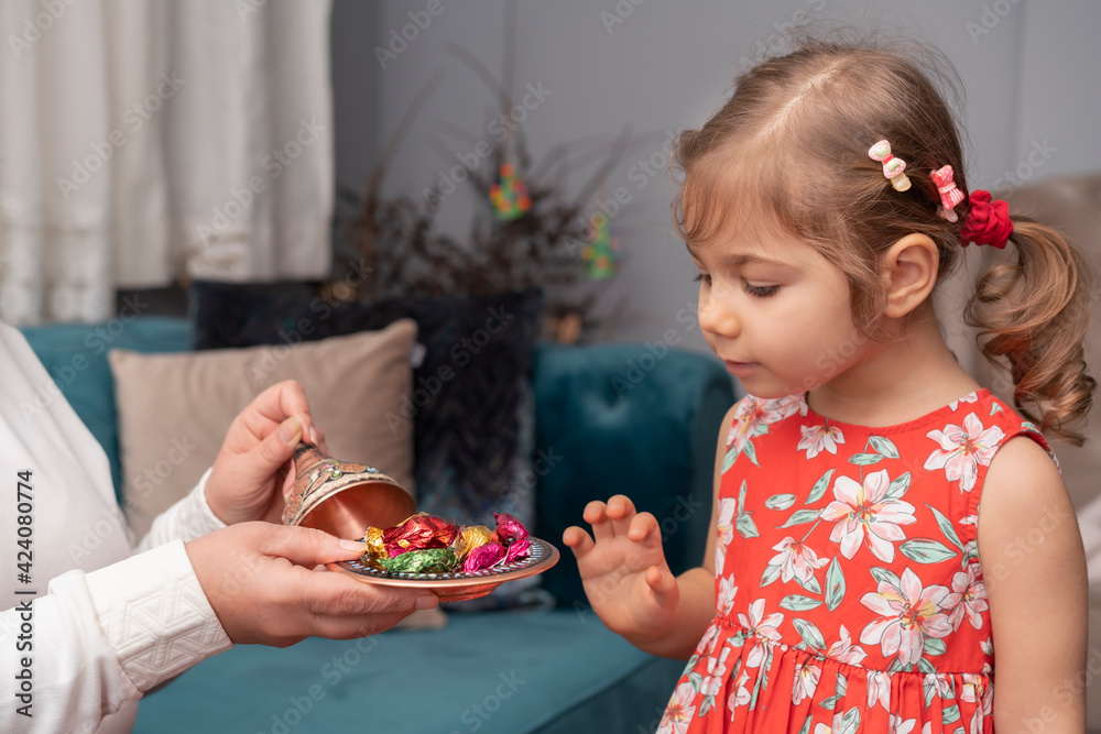 Portrait of cute baby girl holding candies from during Ramadan feast ...