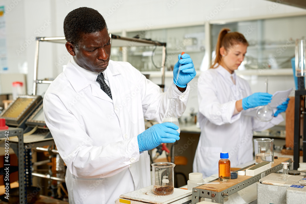 Focused man lab technician in gloves working with reagents and test ...