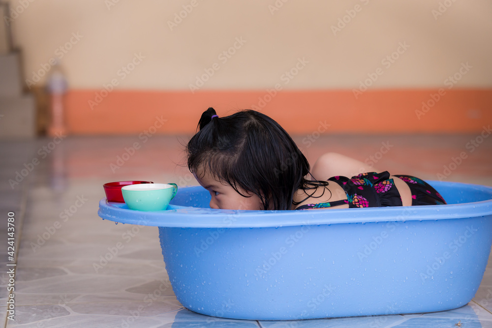Active girl play water in blue plastic basin. Child looks at the ...