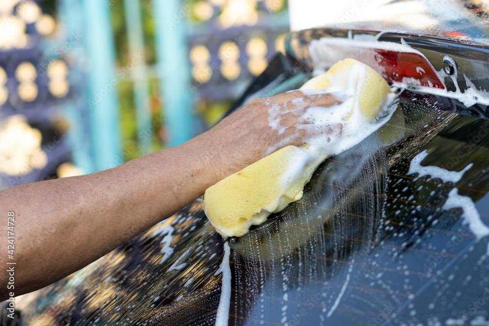 Hand washing car with soapy water. Man cleans car with sponge, water ...