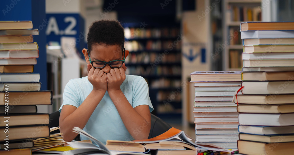 Stressed afro-american teen student crying sitting at table with stack ...