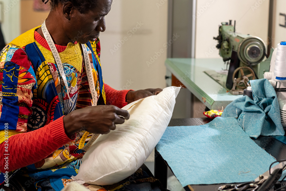 African textile industry artisan at work, tailor taking a measurement ...