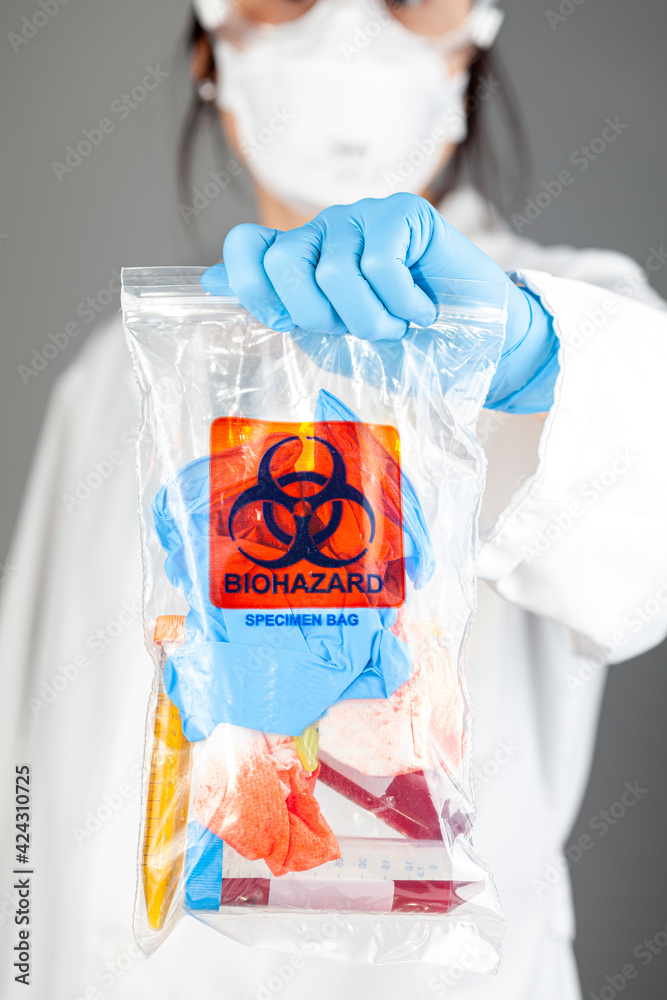 A woman researcher is holding a clear plastic bag with biohazard logo ...