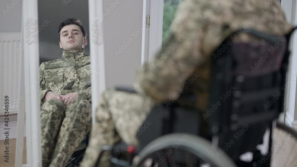 Reflection in mirror of young paraplegic man in wheelchair adjusting ...