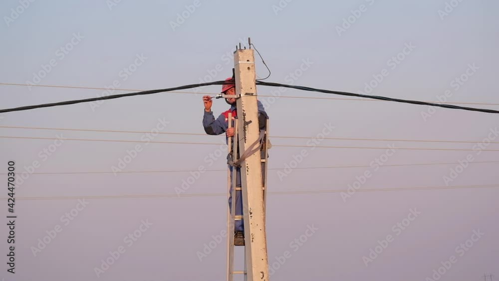 electrical engineer performs installation work on a concrete pillar ...
