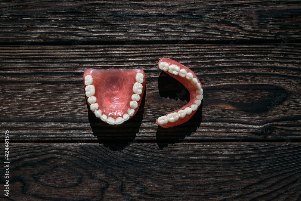 Full removable plastic denture of the jaws. A set of dentures on a dark ...