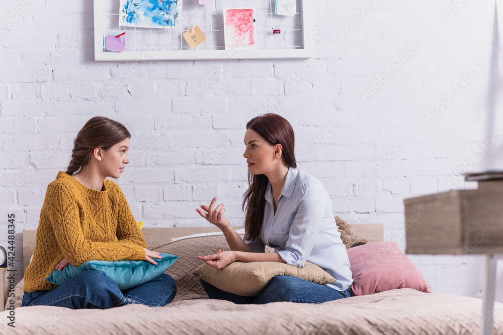 mother gesturing while talking with teenage daughter in bedroom Stock ...