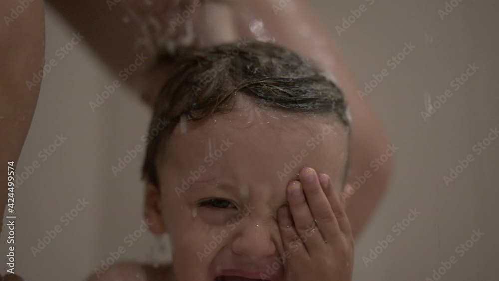 Crying baby washing hair in shower, shampoo itchy eyes in bath. Upset ...