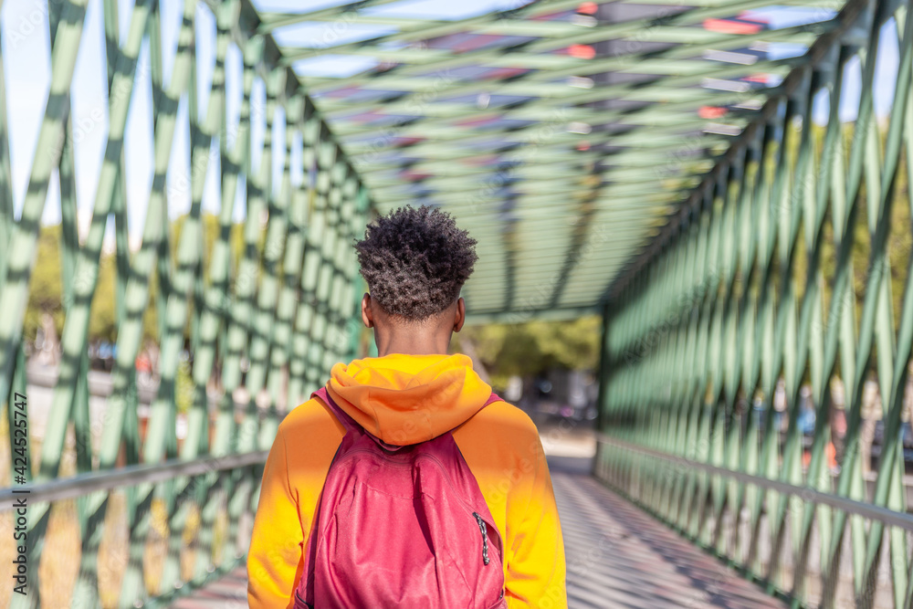 Back view of an afro style boy walking inside a metal bridge Stock ...