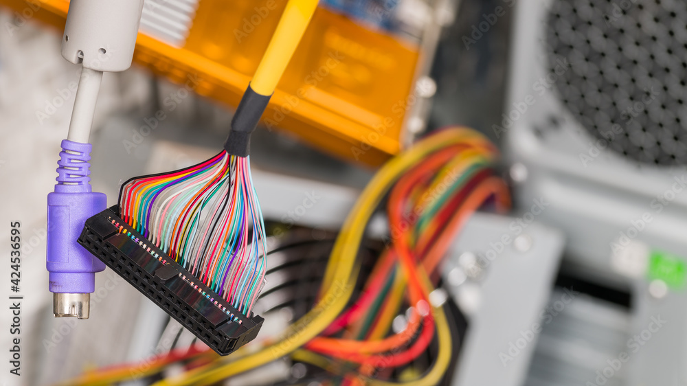 Colored hanging cables with connectors on e-waste heap background ...