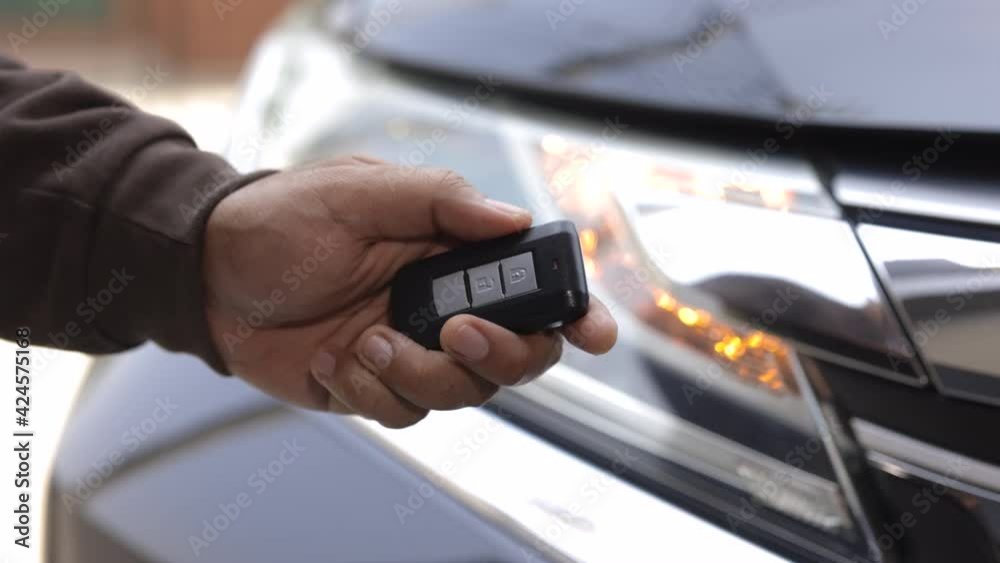 Close up male hand holding car key. Man unlock car door by remote key ...