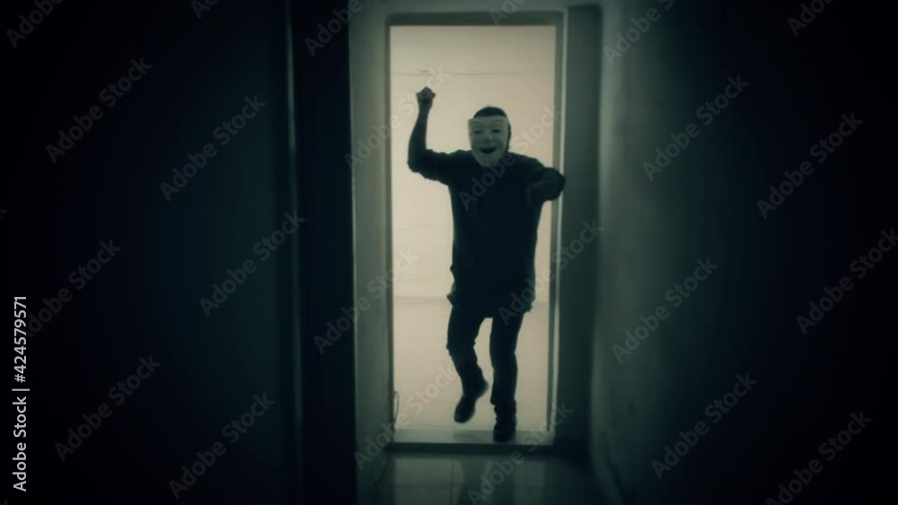 A scary horrifying encounter with a killer in a dark basement, wearing ...