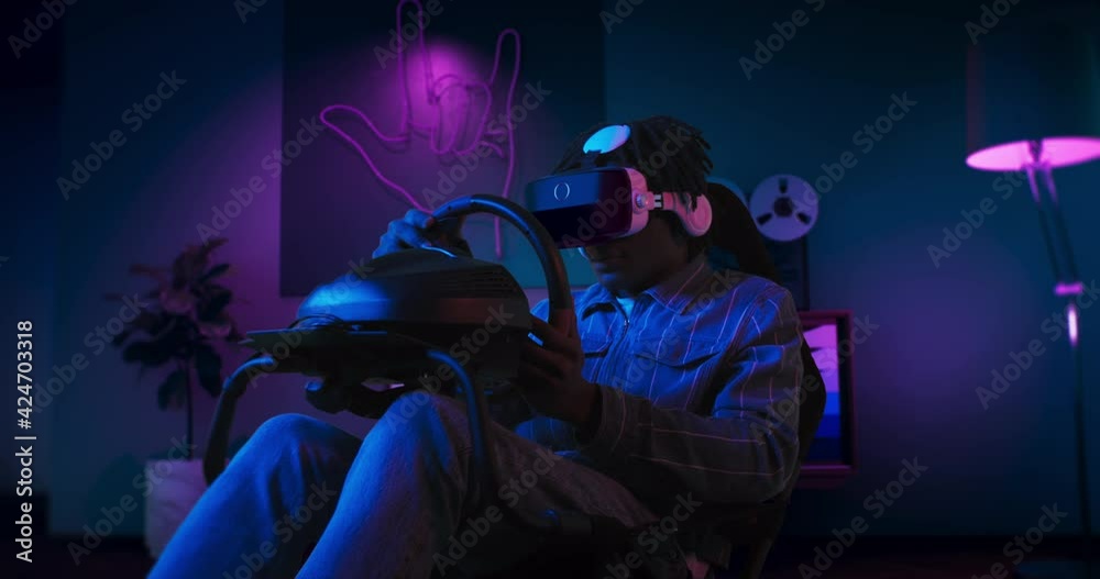 A guy is playing racing game in VR. He is sitting on the gaming chair ...