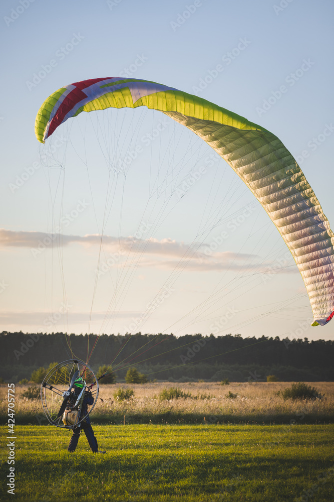 A pilot with a petrol powered backpack landed and folds the wing ...