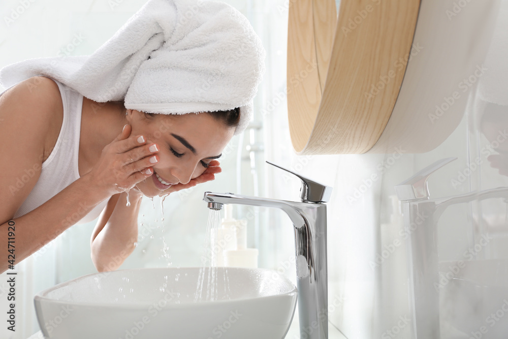 Happy young woman washing face in bathroom Stock Photo | Adobe Stock