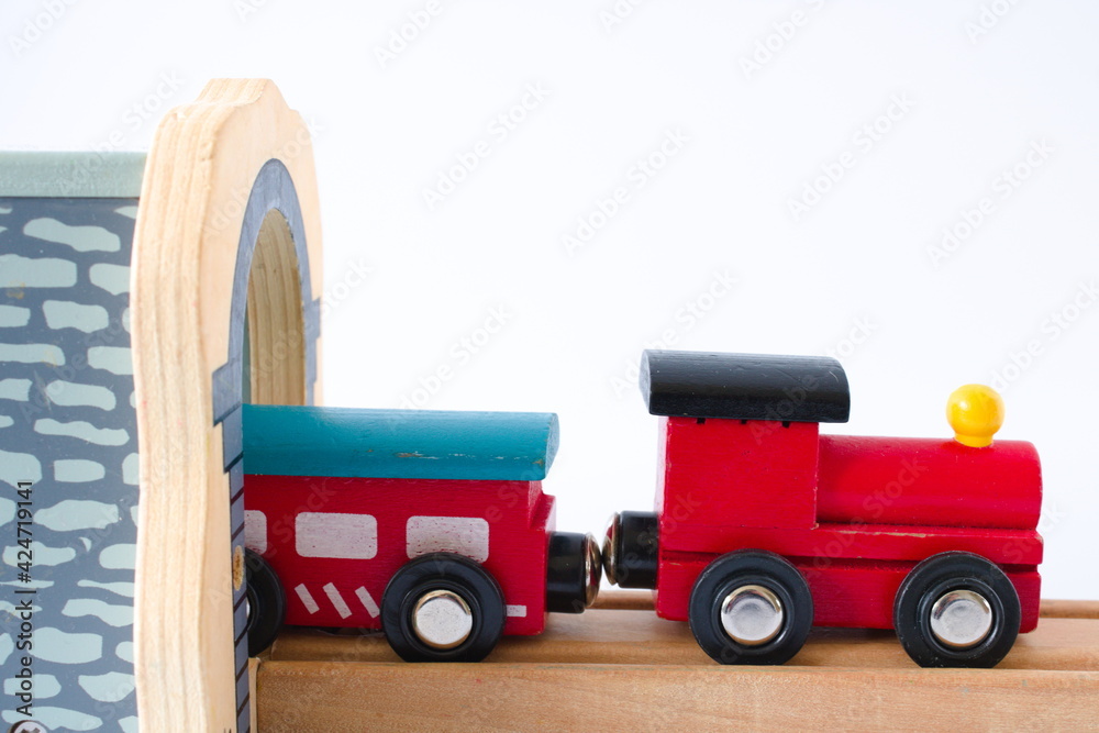Red wooden toy train, side view, leaving the tunnel on train tracks ...