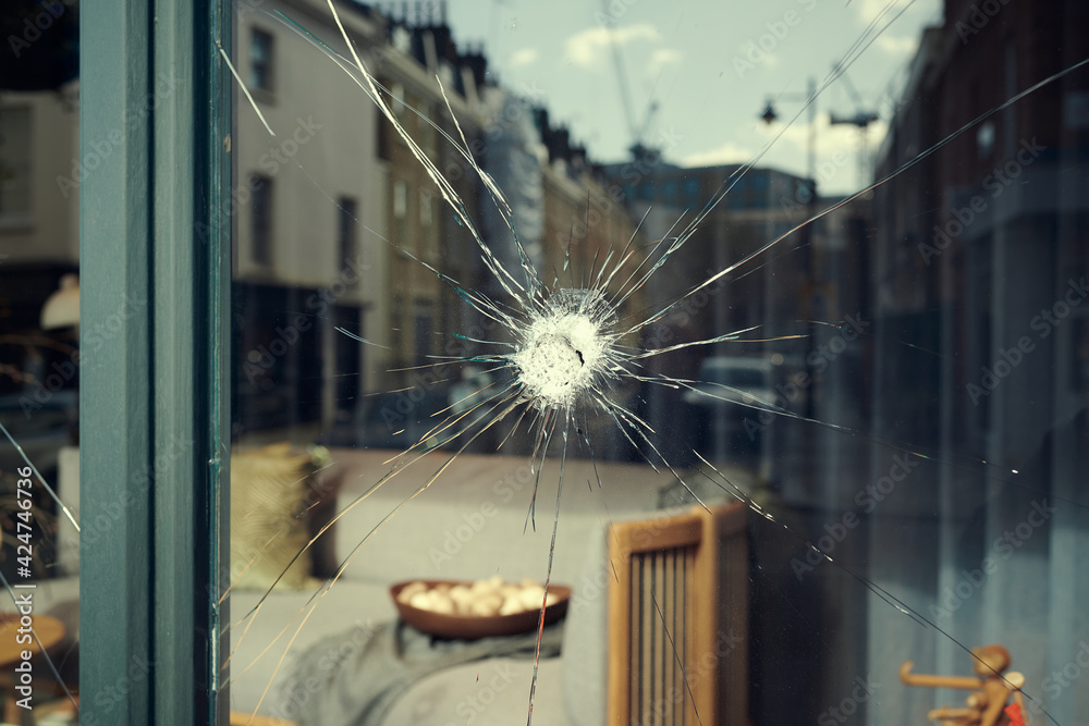 Broken shop window pane that looks like a bullet hole with sunlight ...