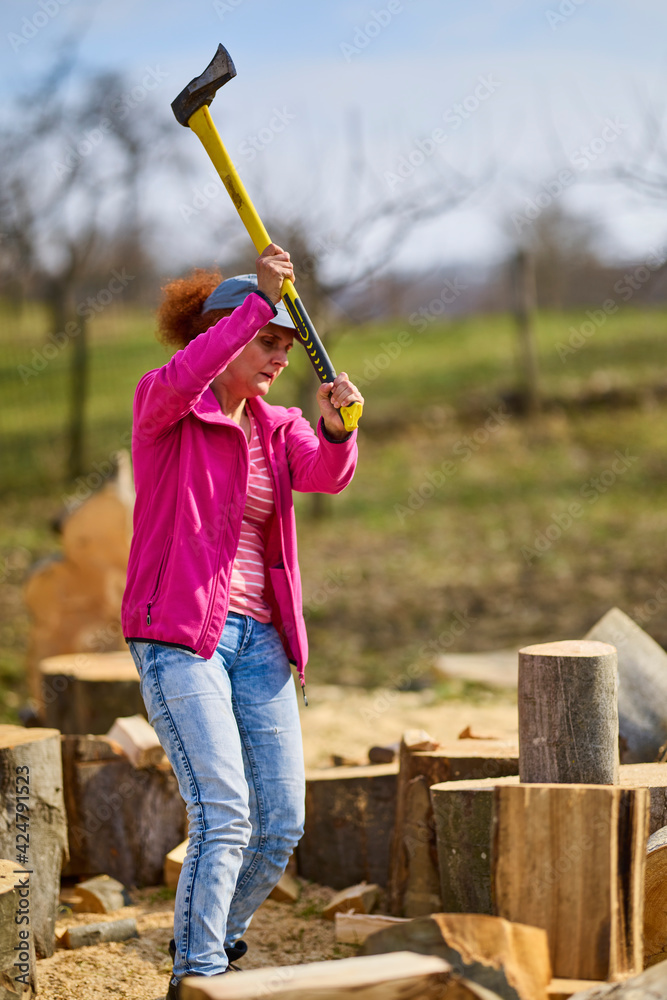 Strong woman splitting beech logs for firewood Stock Photo | Adobe Stock