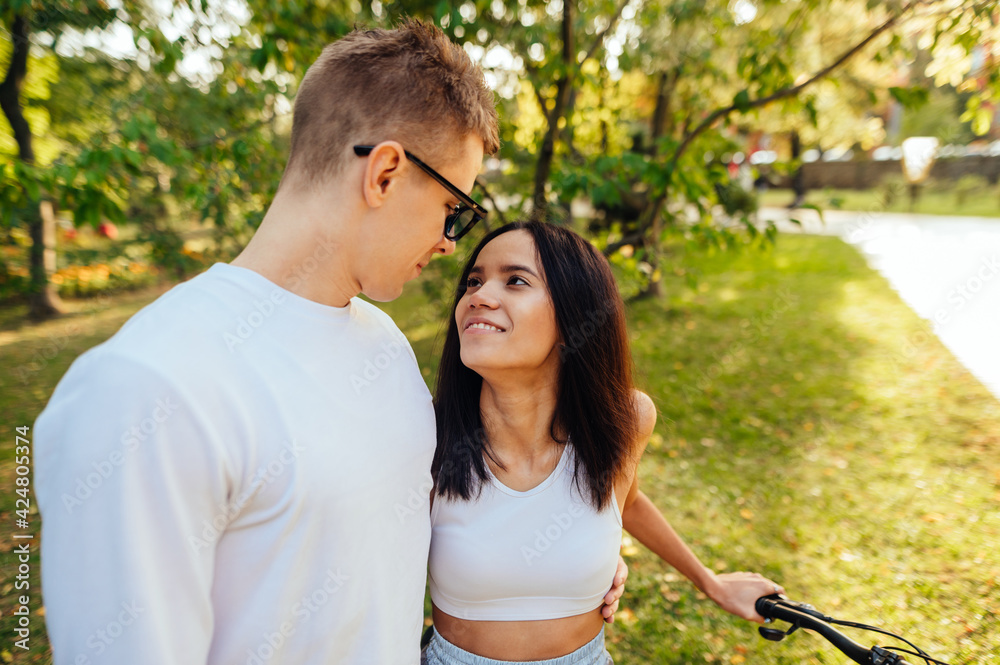 Lovely couple is standing in the park, smiling, looking at each other ...