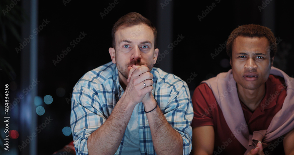 Multi-cultural stressed young men in row worrying for favorite football ...