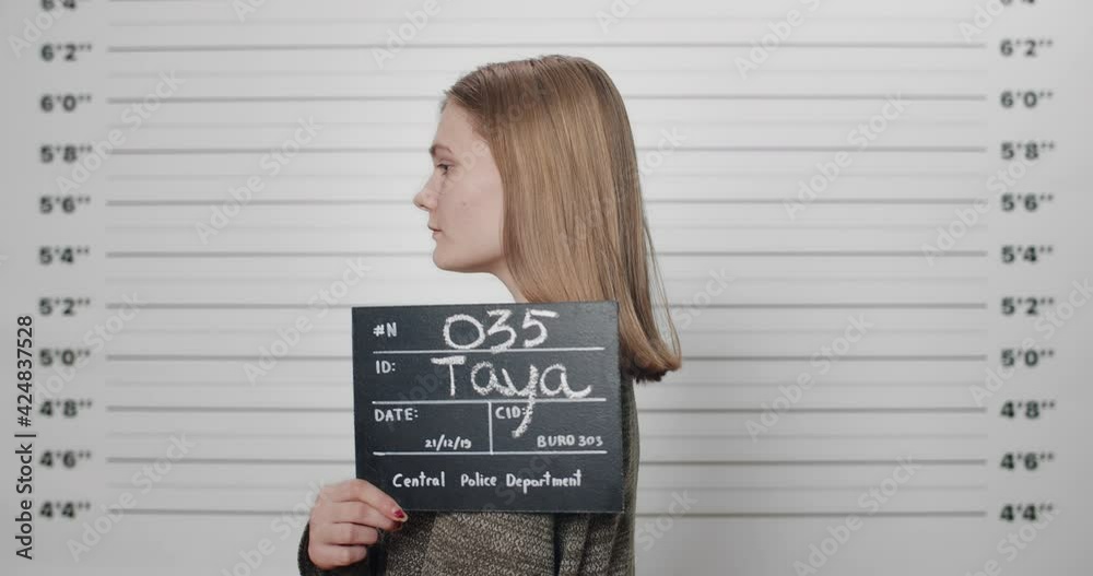 Mugshot of arrested female person holding sign while being photographed ...