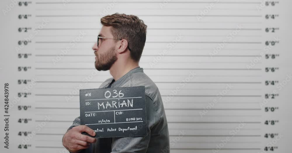 Side profile mugshot of man with beard and mustache standing at metric ...