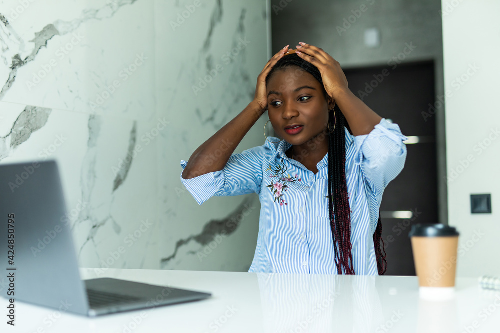 African american woman using computer laptop at kitchen stressed with ...