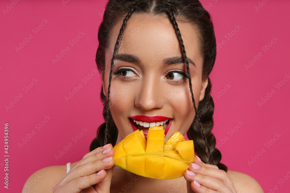 Young woman eating fresh mango on pink background. Exotic fruit Stock-Foto | Adobe Stock