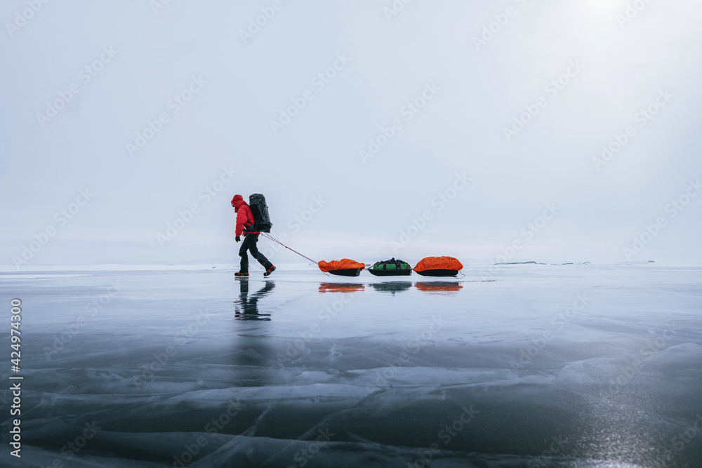 Tourist walking with sleigh dragging on the frozen ice of Lake Baikal ...