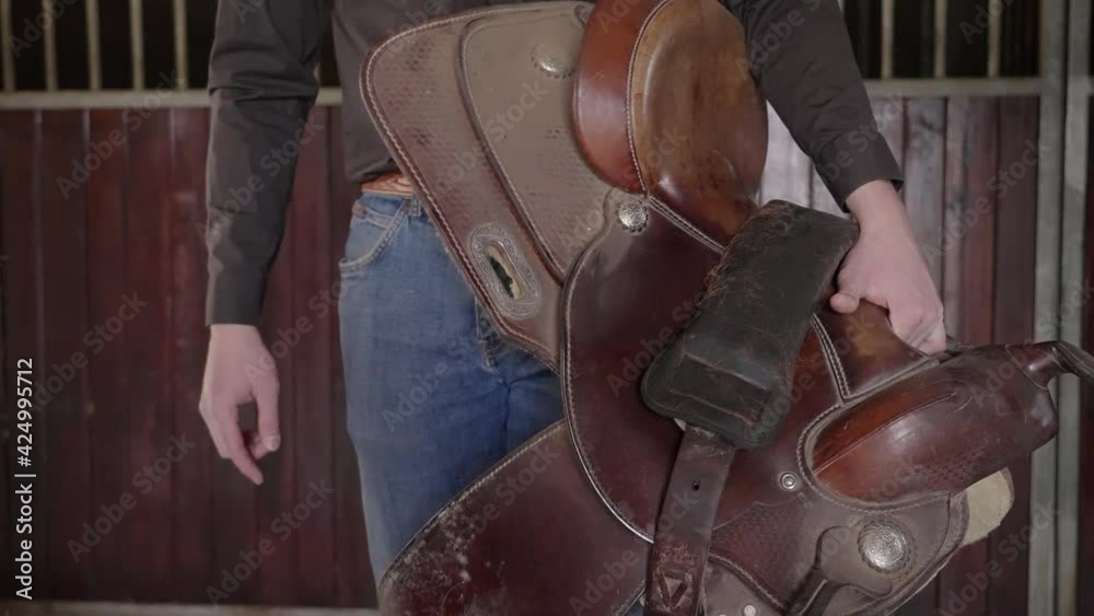 Cowboy carry western saddle under arm from barn 4K Stock ビデオ | Adobe Stock