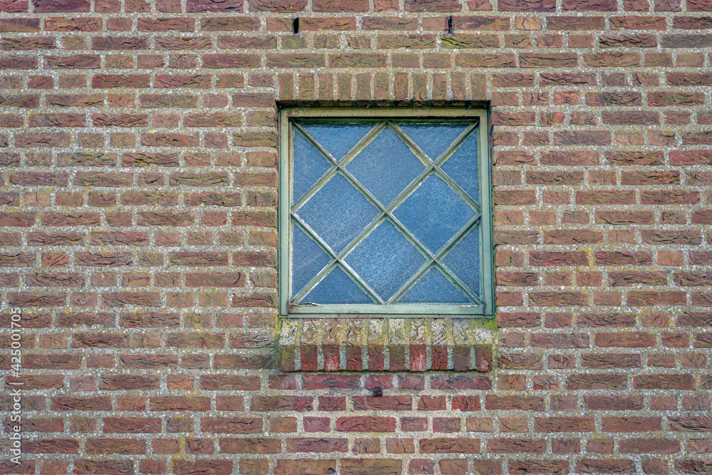 Old square window with glazing bars in a masonry brick wall. The light ...
