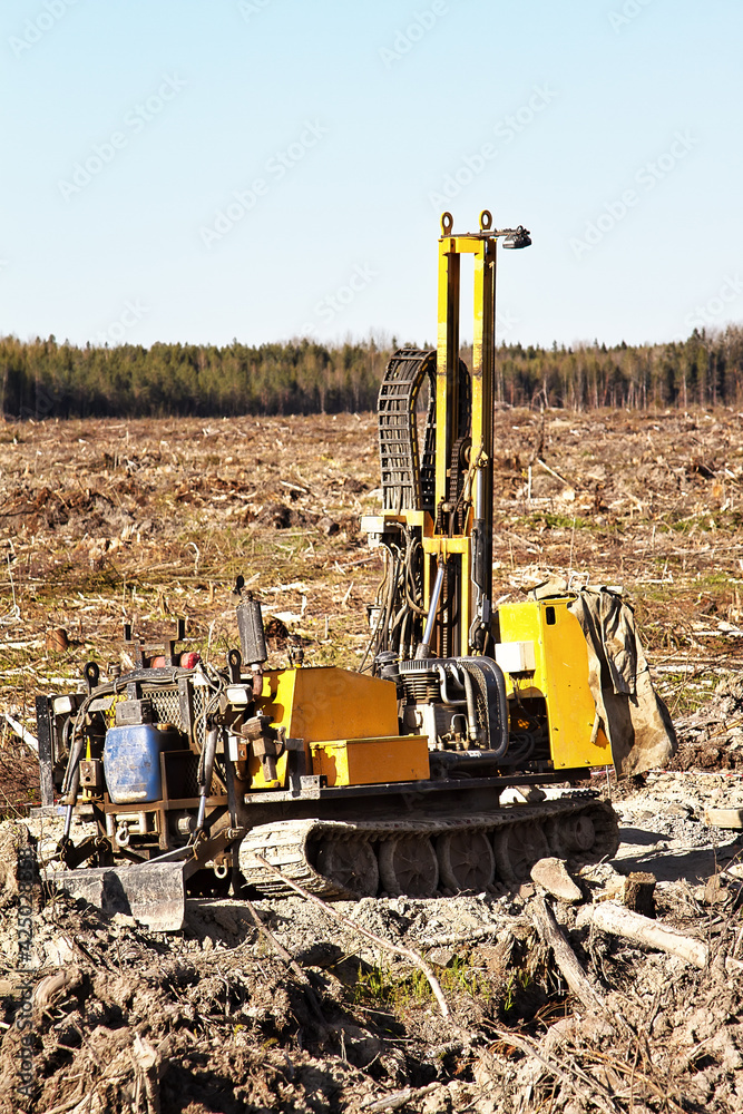 Mini-drilling rig on crawler track on site of sawn forest where large ...