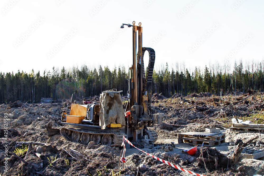 Mini-drilling rig on crawler track on site of sawn forest where large ...