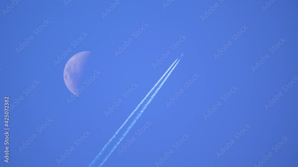 Plane Flies In Front Of Moon In daytime. Airliner flying high and moon ...